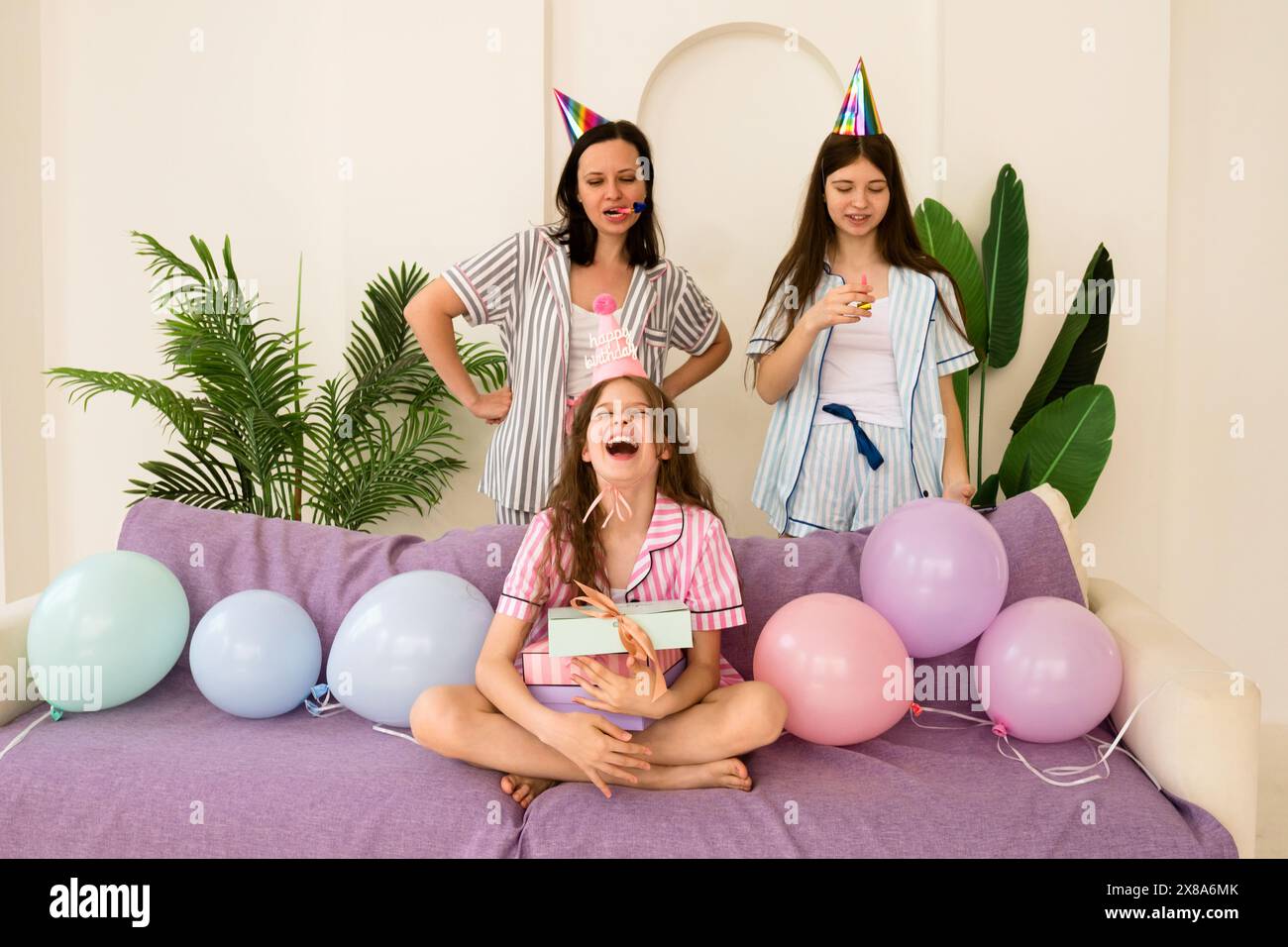 Laughing family with party accessories celebrating a birthday at home ...