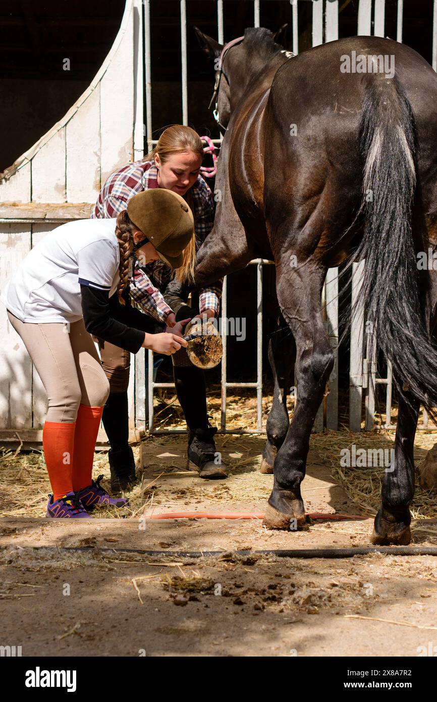 A young girl in a helmet receives guidance from an instructor while ...