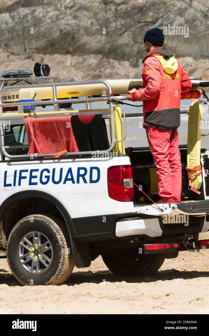 A RNLI Lifeguard on duty standing on his emergency response vehicle ...