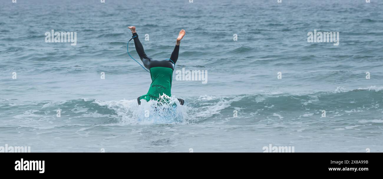 A panoramic image of an enthusiastic surfer attempting a headstand on ...
