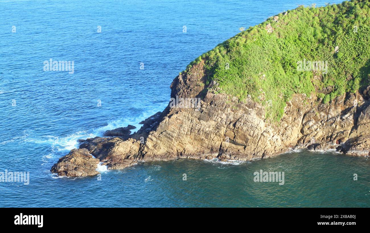 aerial view of the edge of a green island in the middle of the ocean ...