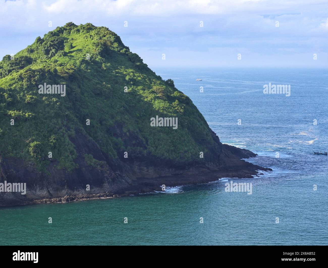 aerial view of the edge of a green island in the middle of the ocean ...