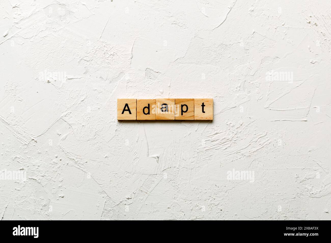 ADAPT word written on wood block. ADAPT text on cement table for your ...