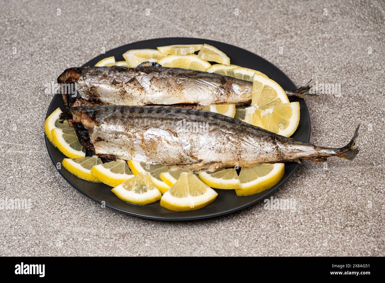 Oven-baked mackerel sea fish dish served with fresh lemon slices Stock ...