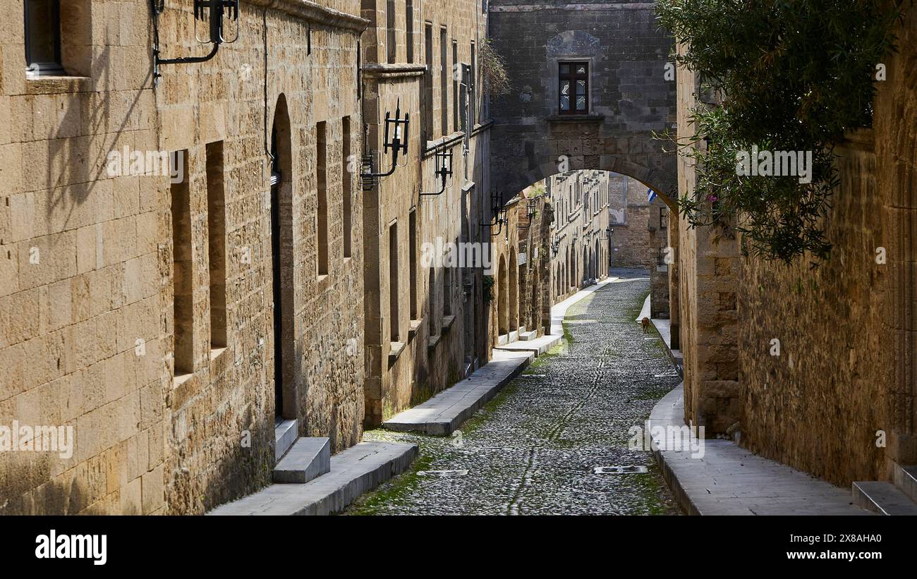 Historic, narrow street with stone buildings and an arch, deserted ...