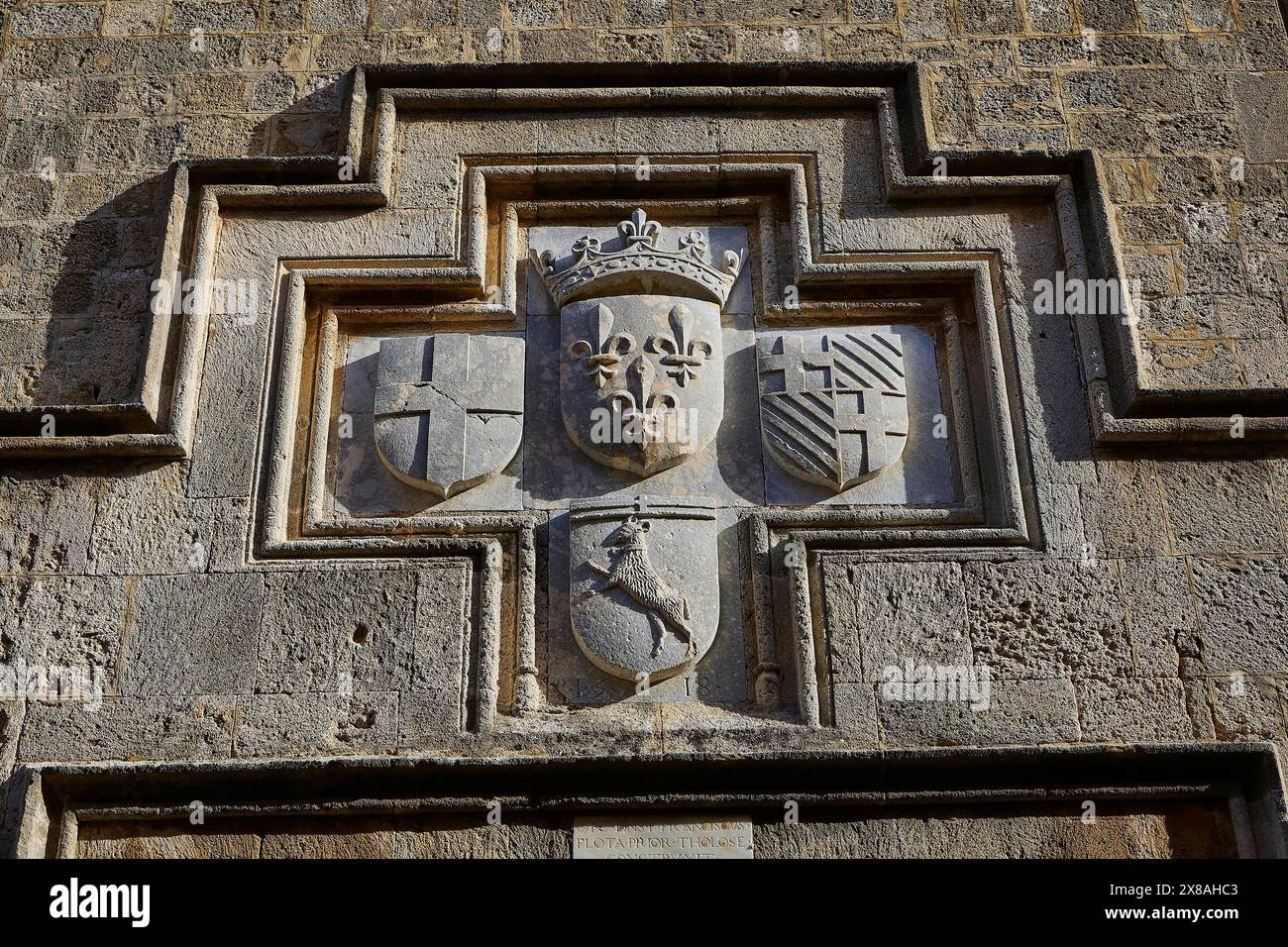 A coat of arms carved into a stone wall with various historical symbols ...