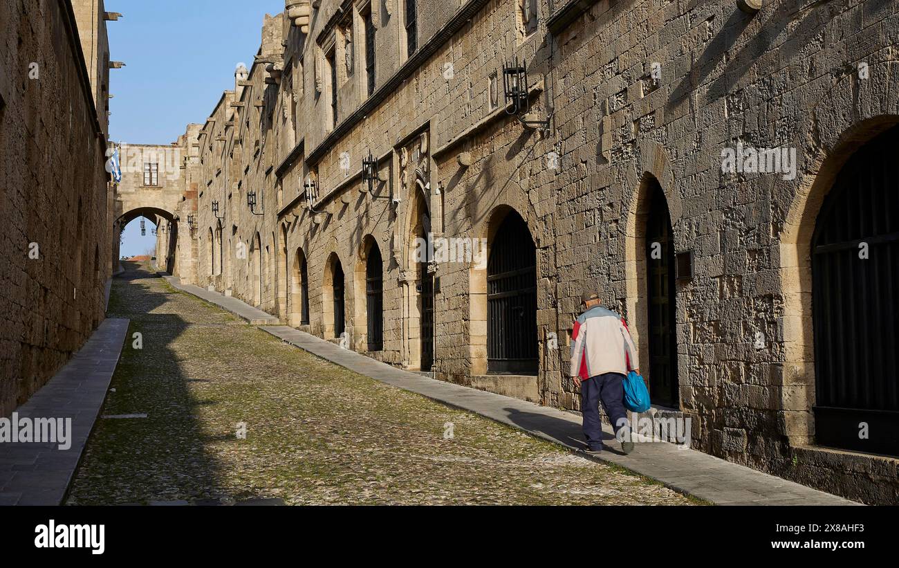 A historic alley with stone buildings, a pedestrian walks along the ...