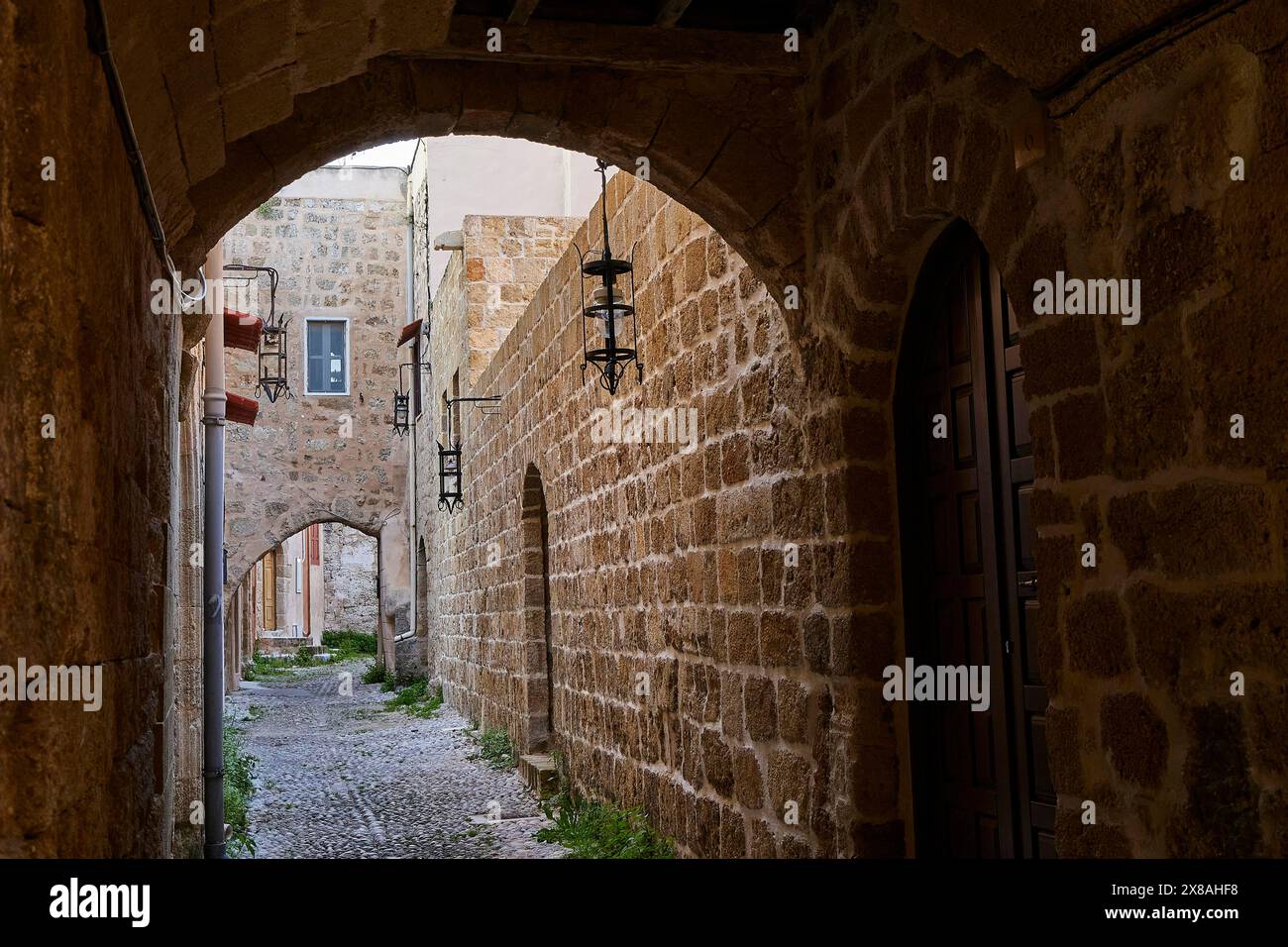 A narrow, stone passageway leads through an alley paved with ...