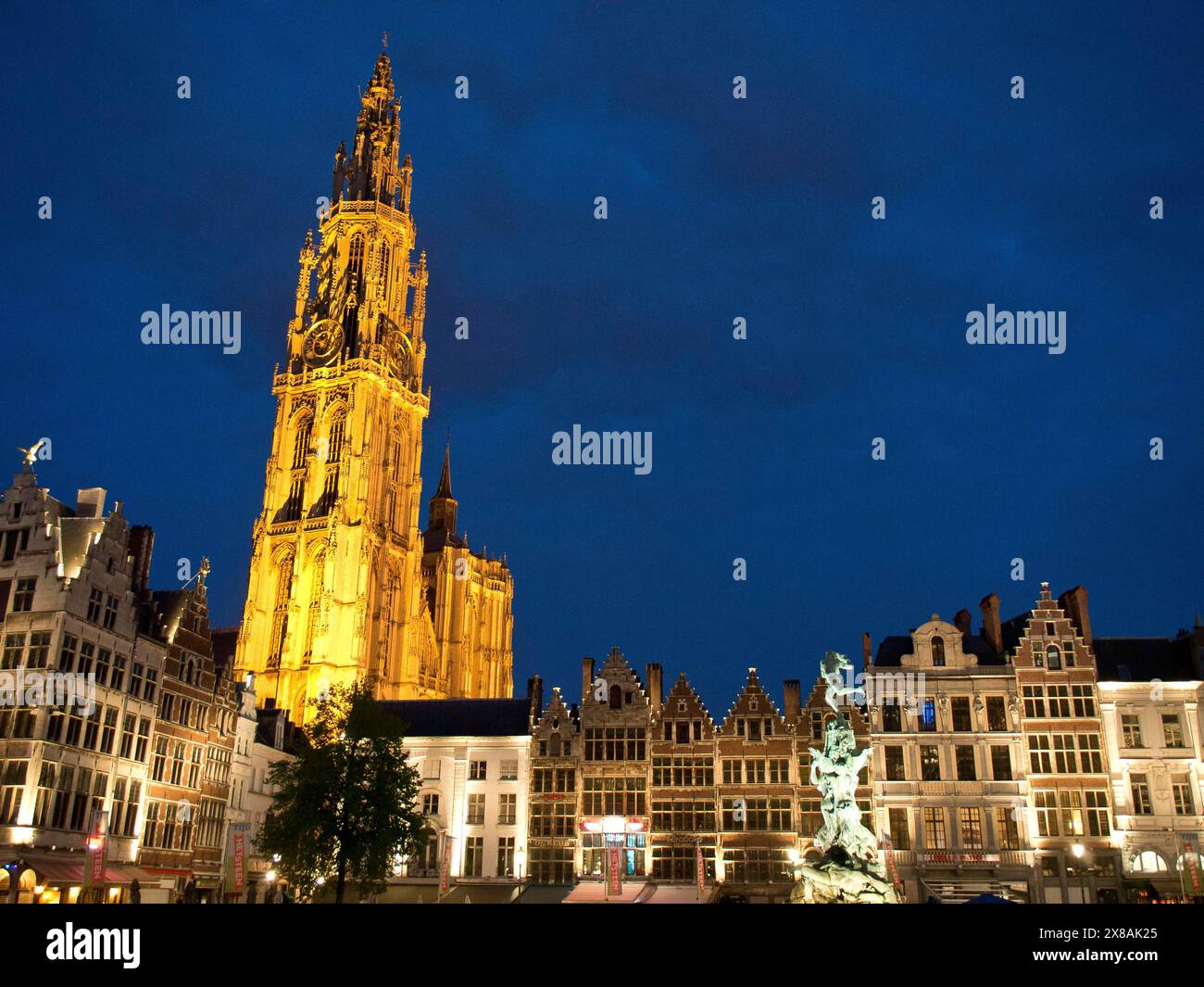 A tall, illuminated tower next to historic buildings in the city centre ...