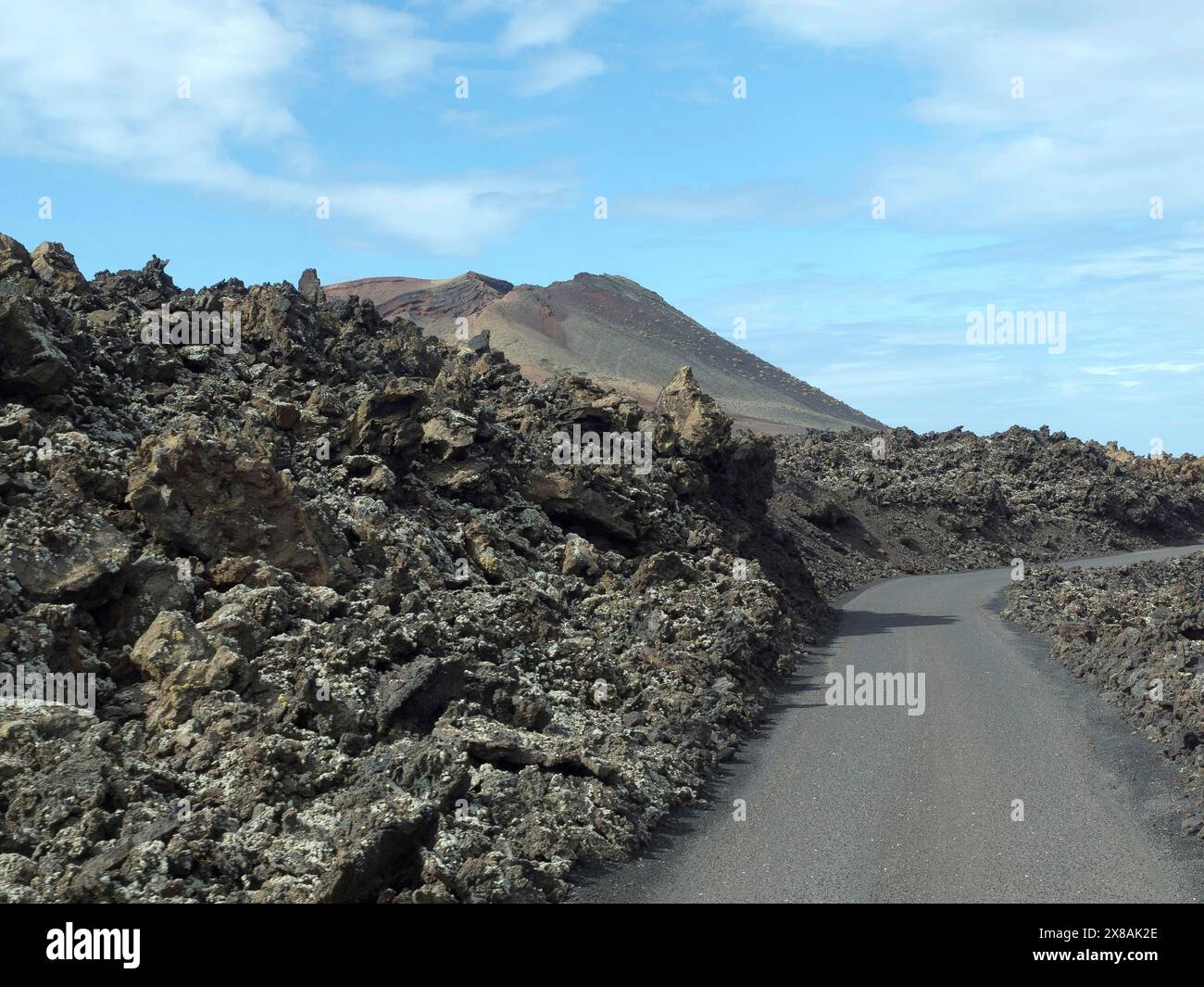 Road leading through a volcanic landscape, surrounded by dark lava rock ...