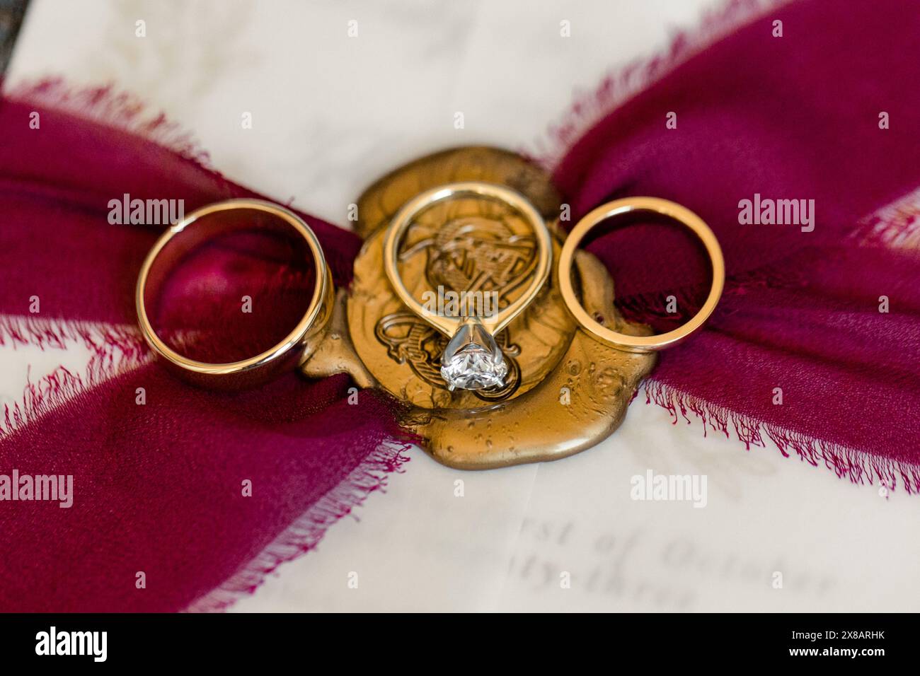 Wedding rings with a seal on burgundy ribbon Stock Photo - Alamy