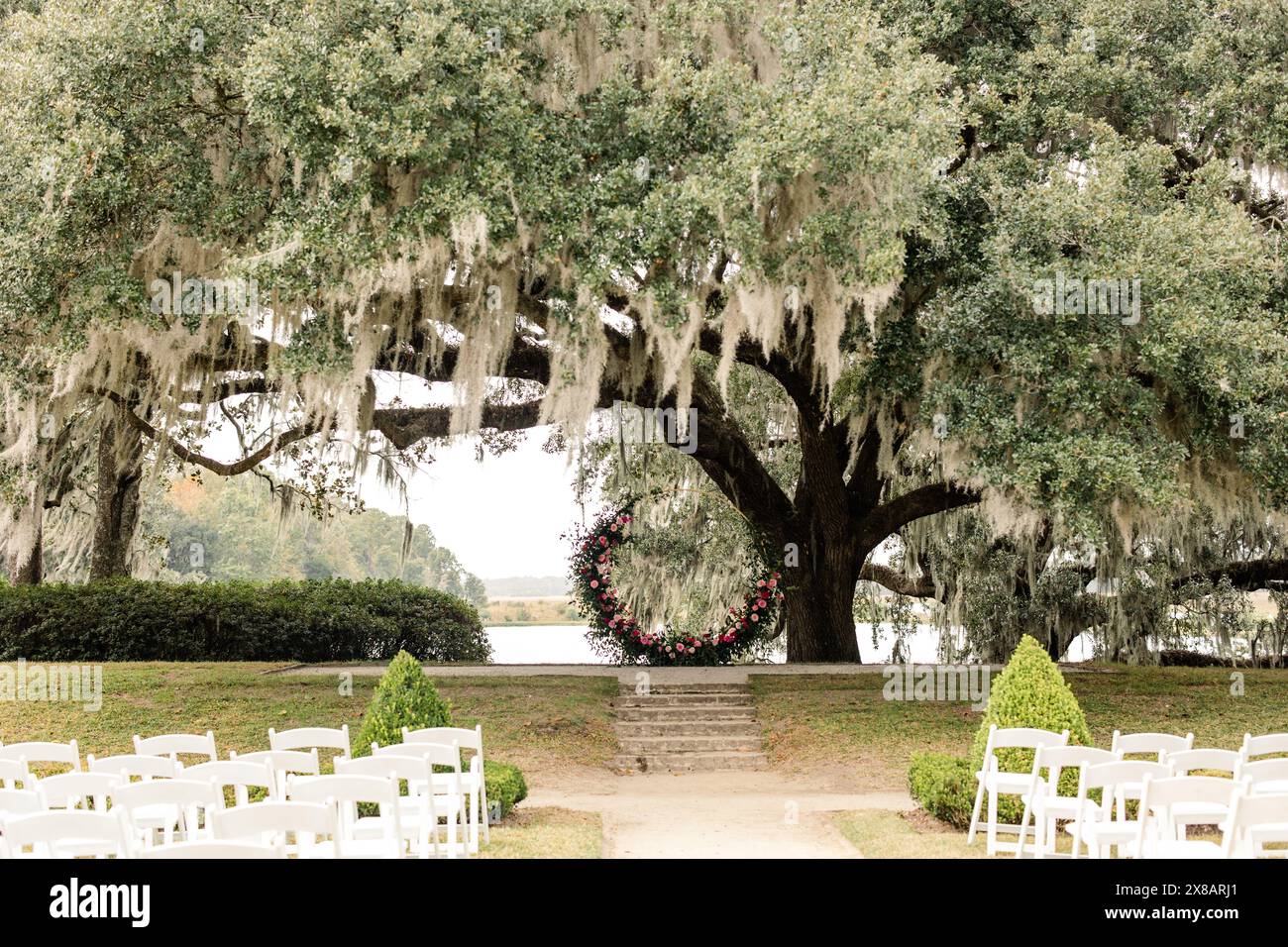 Outdoor wedding ceremony setup under oak tree with floral arch Stock ...