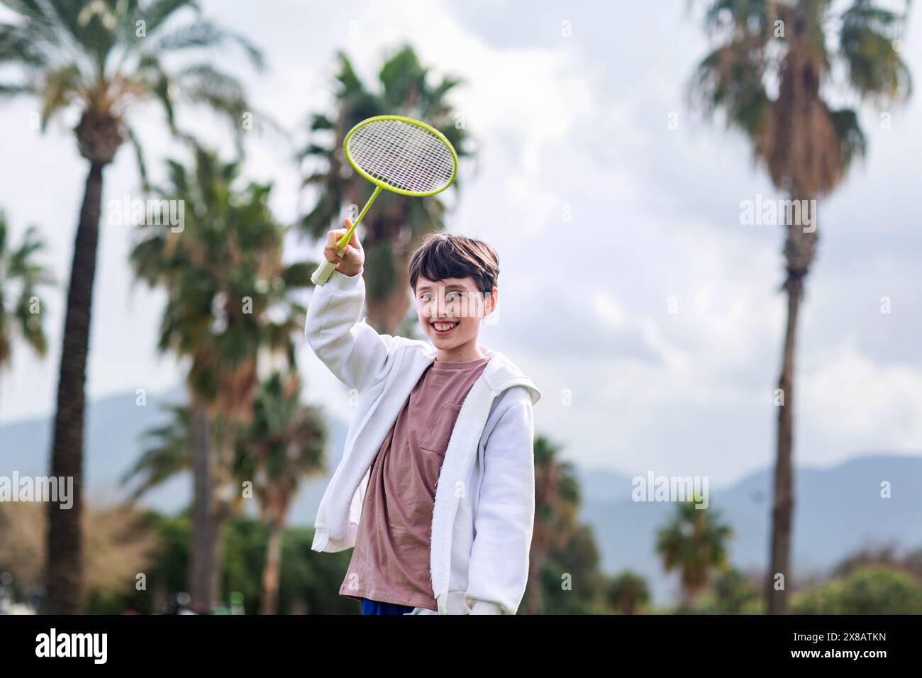teenager boy with badminton racket smiling on palm background Stock ...