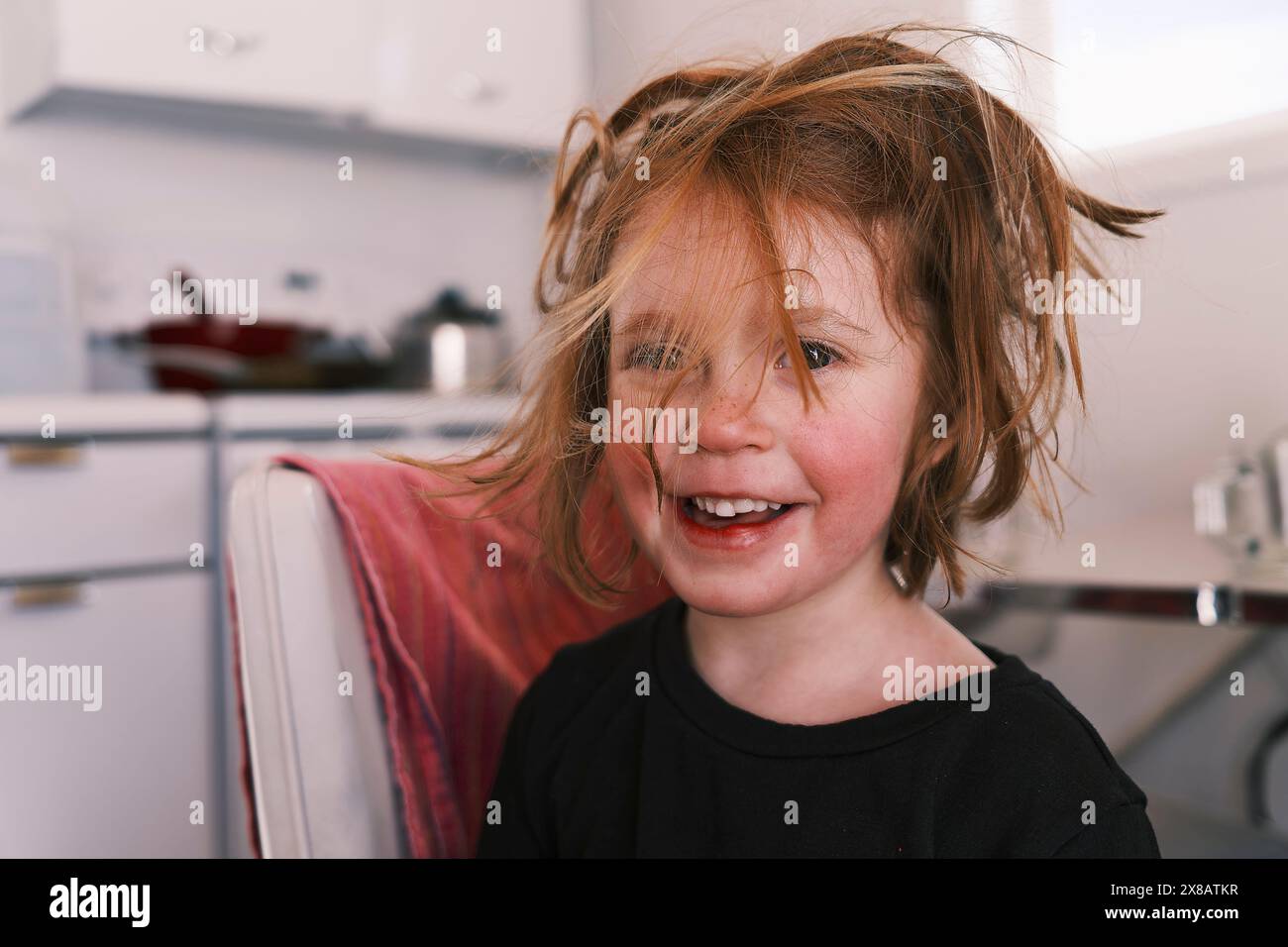 Happy young child with messy hair smiling in kitchen Stock Photo - Alamy