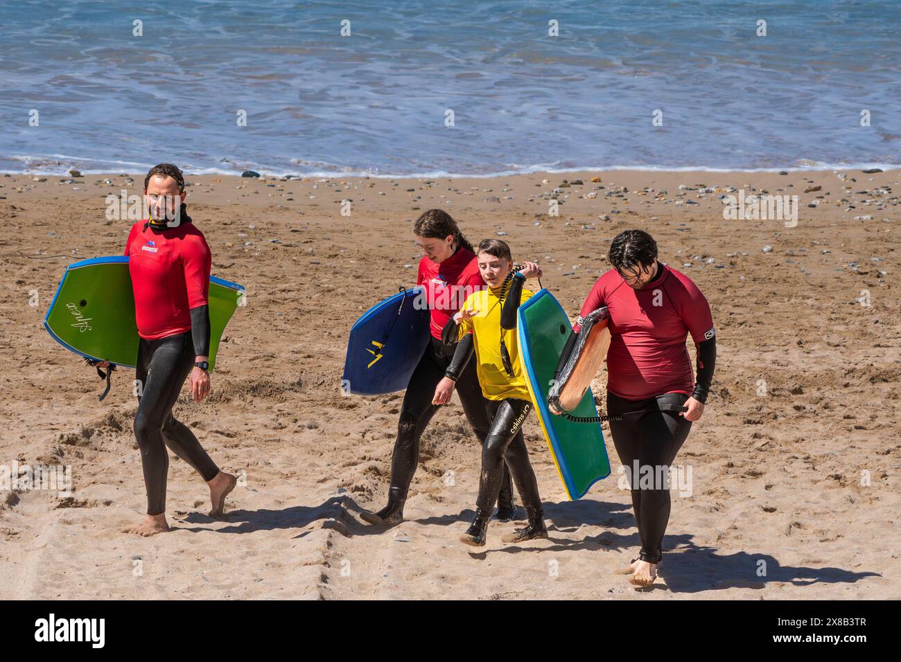 A surfing instructor with novices after a body boogie boarding lesson ...