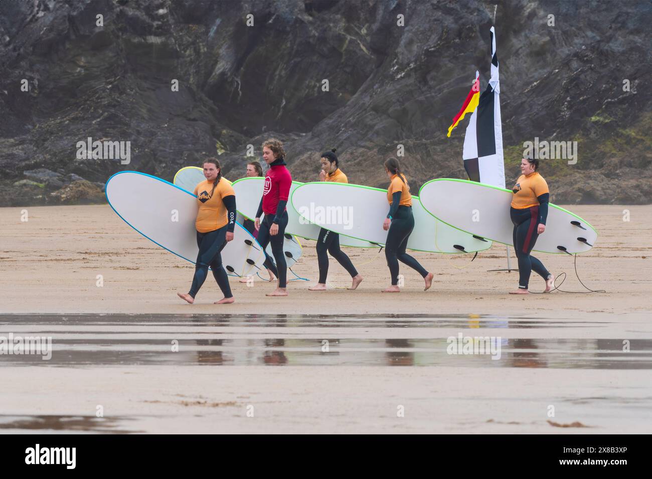 Novice surfers carrying their surfboards and walking with their surfing ...