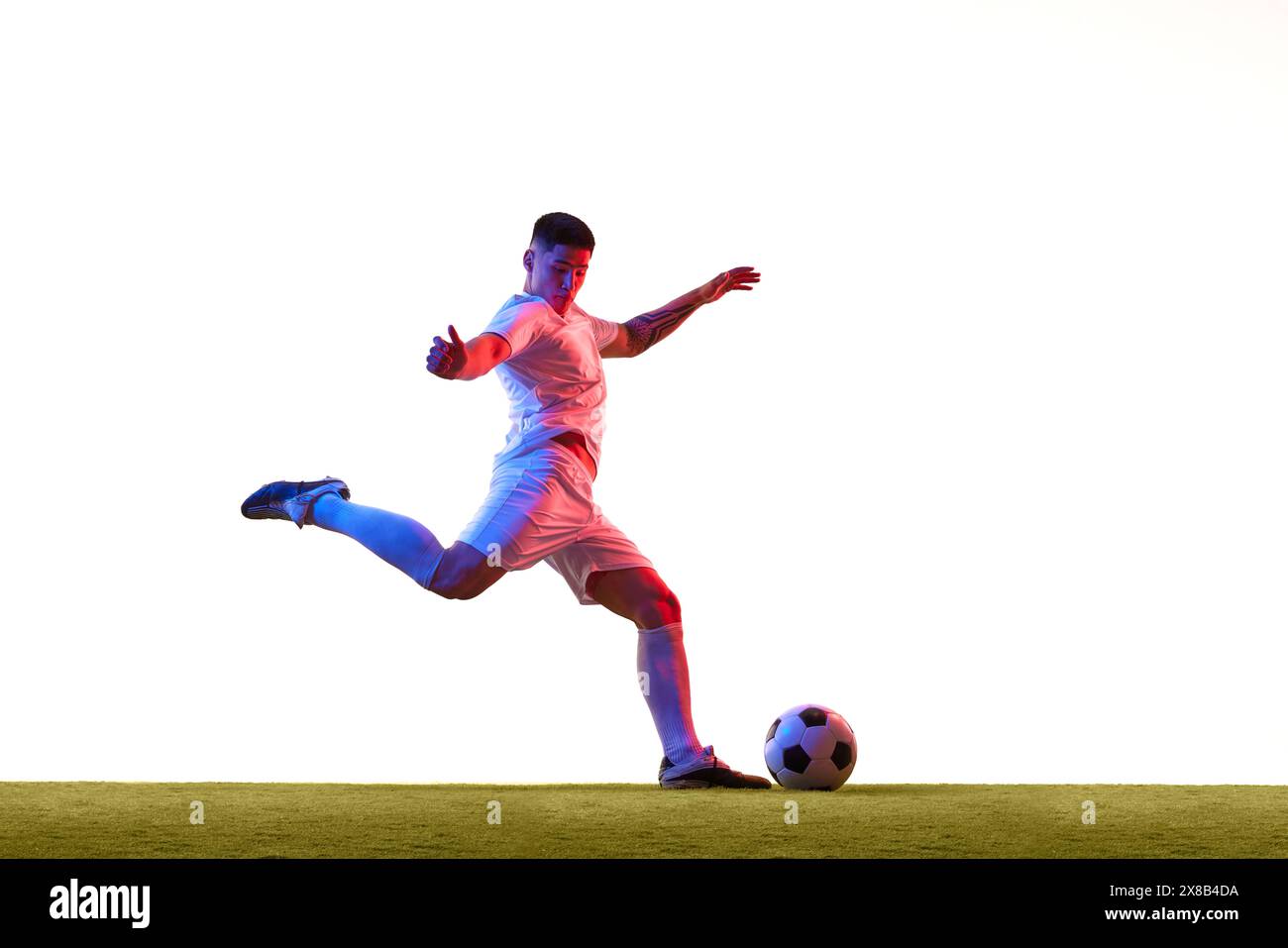 Soccer player in green shorts and white jersey, captured mid-kick on ...