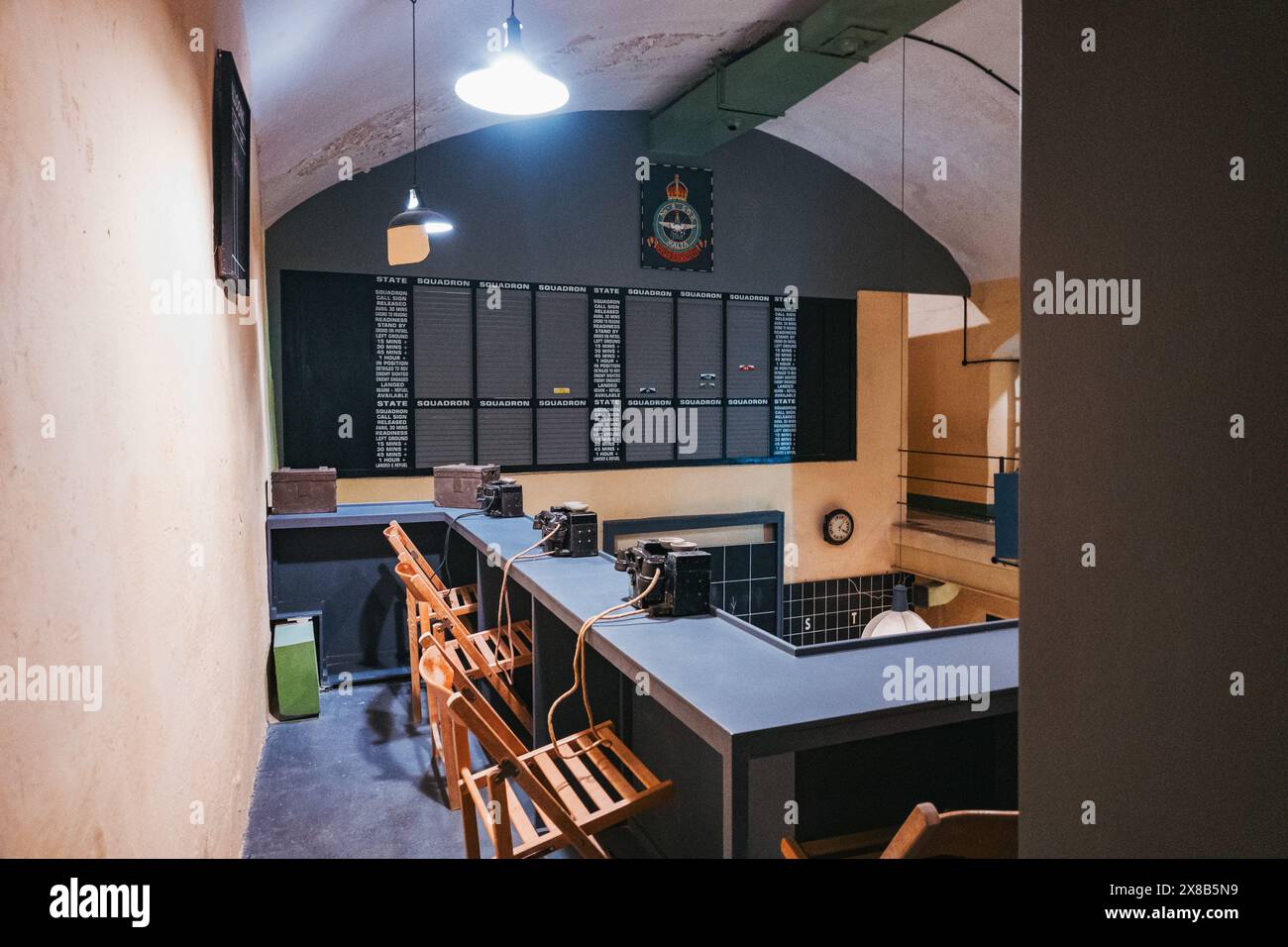 A World War II era command center with a long table, telephones, chairs ...