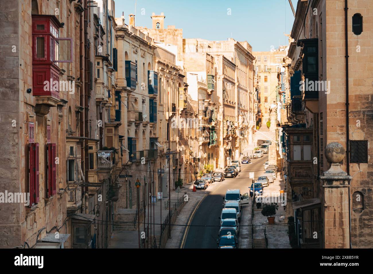 a street curves through the city of Sliema, Malta, lined with limestone ...