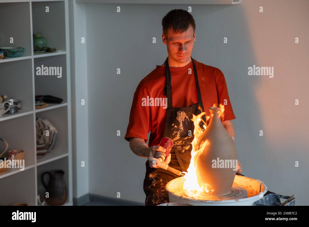 A potter burns a jug with a gas burner on a potter's wheel Stock Photo ...