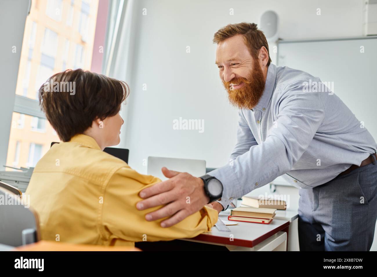 A man in a classroom setting encouraging boy, symbolizing mentorship ...