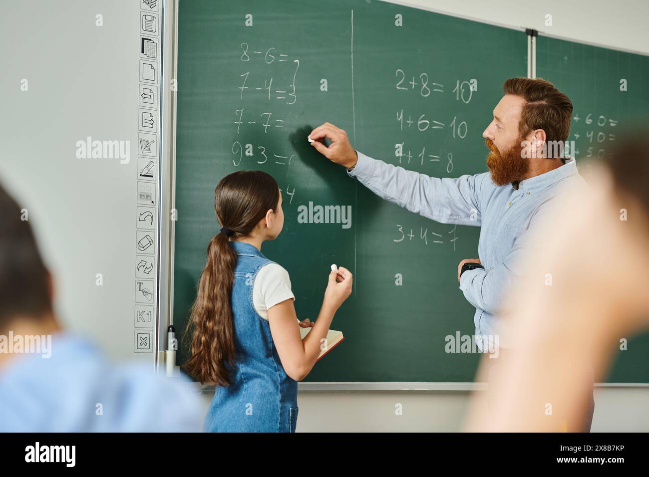 A man in colorful attire teaches a group of kids by a blackboard in a ...