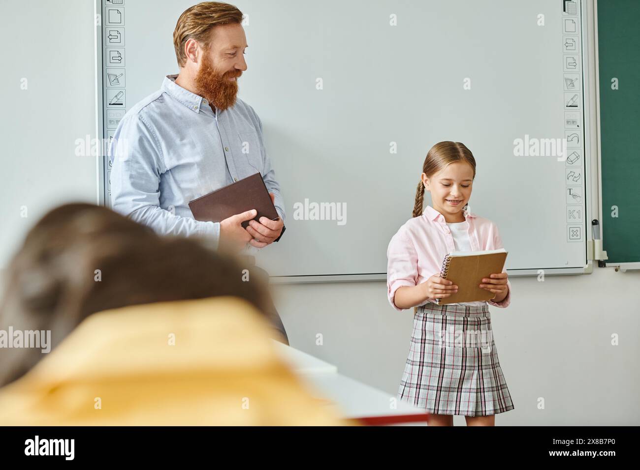 A man stands beside a little girl in front of a whiteboard in a vibrant ...
