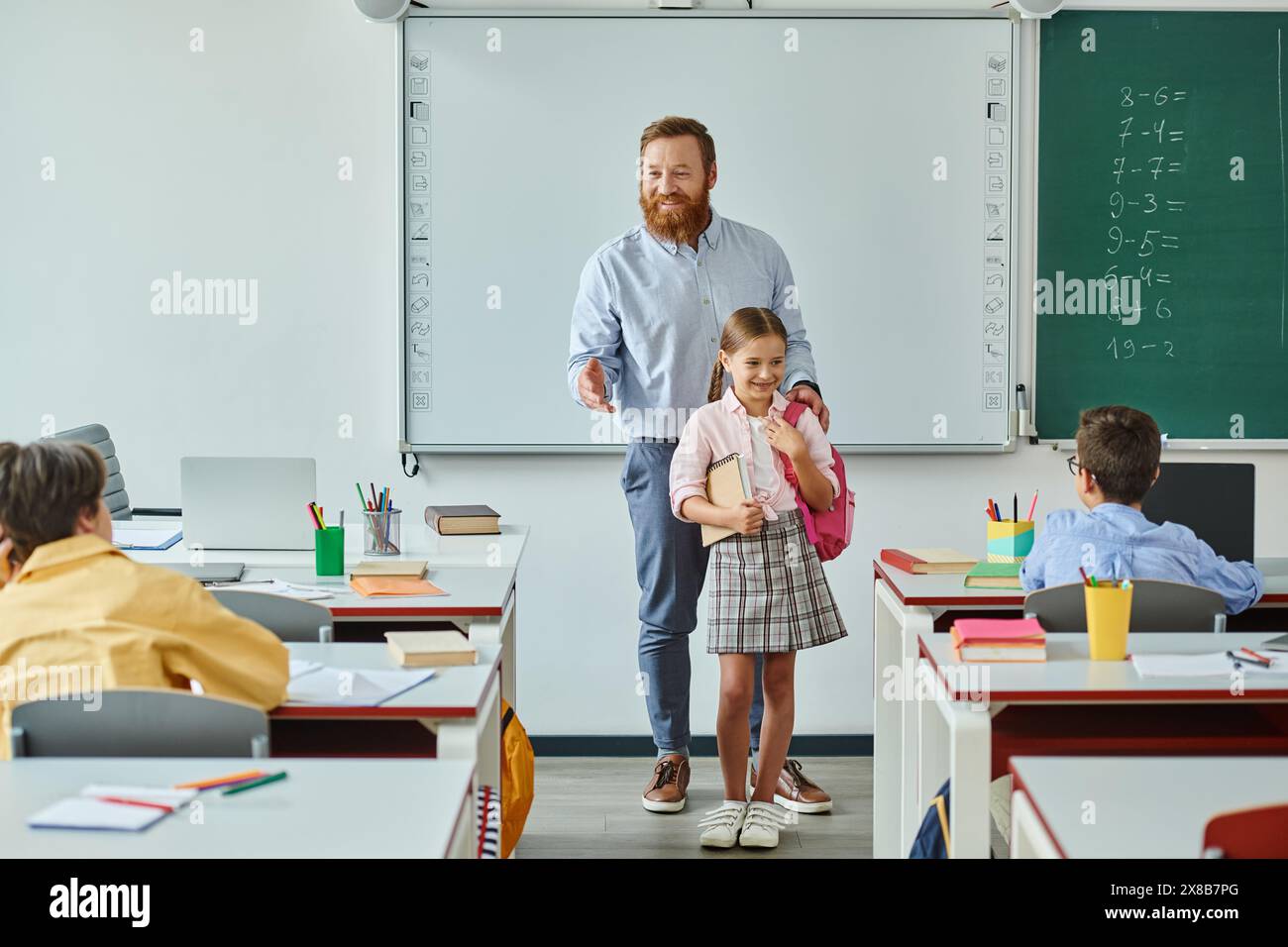 A man teacher stands beside a young girl in a vibrant classroom setting ...