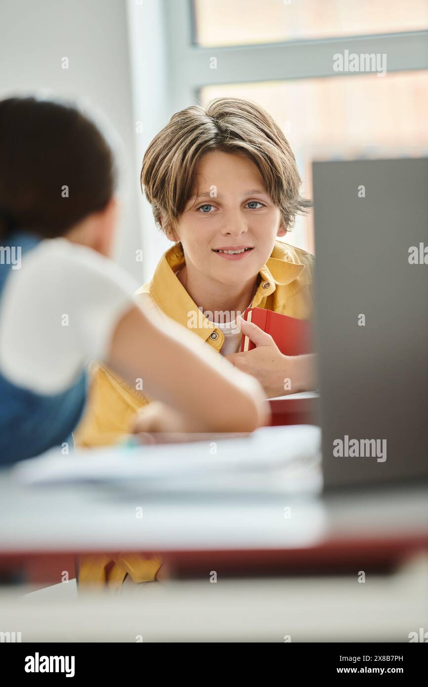 A young boy sits at a desk in a vibrant classroom, engrossed in his ...