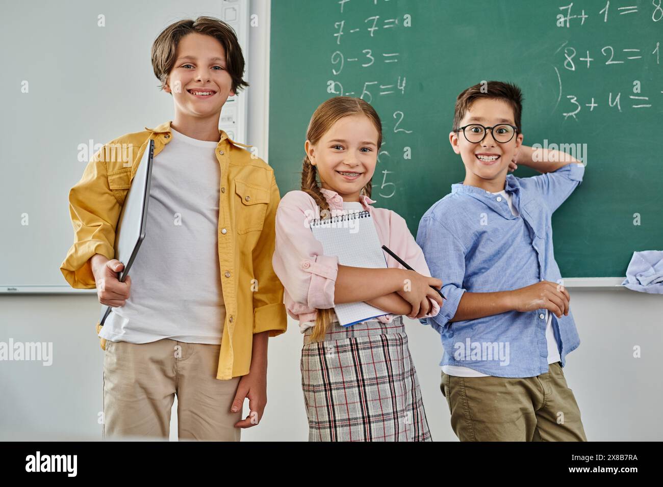A group of children stand attentively in front of a chalkboard in a ...
