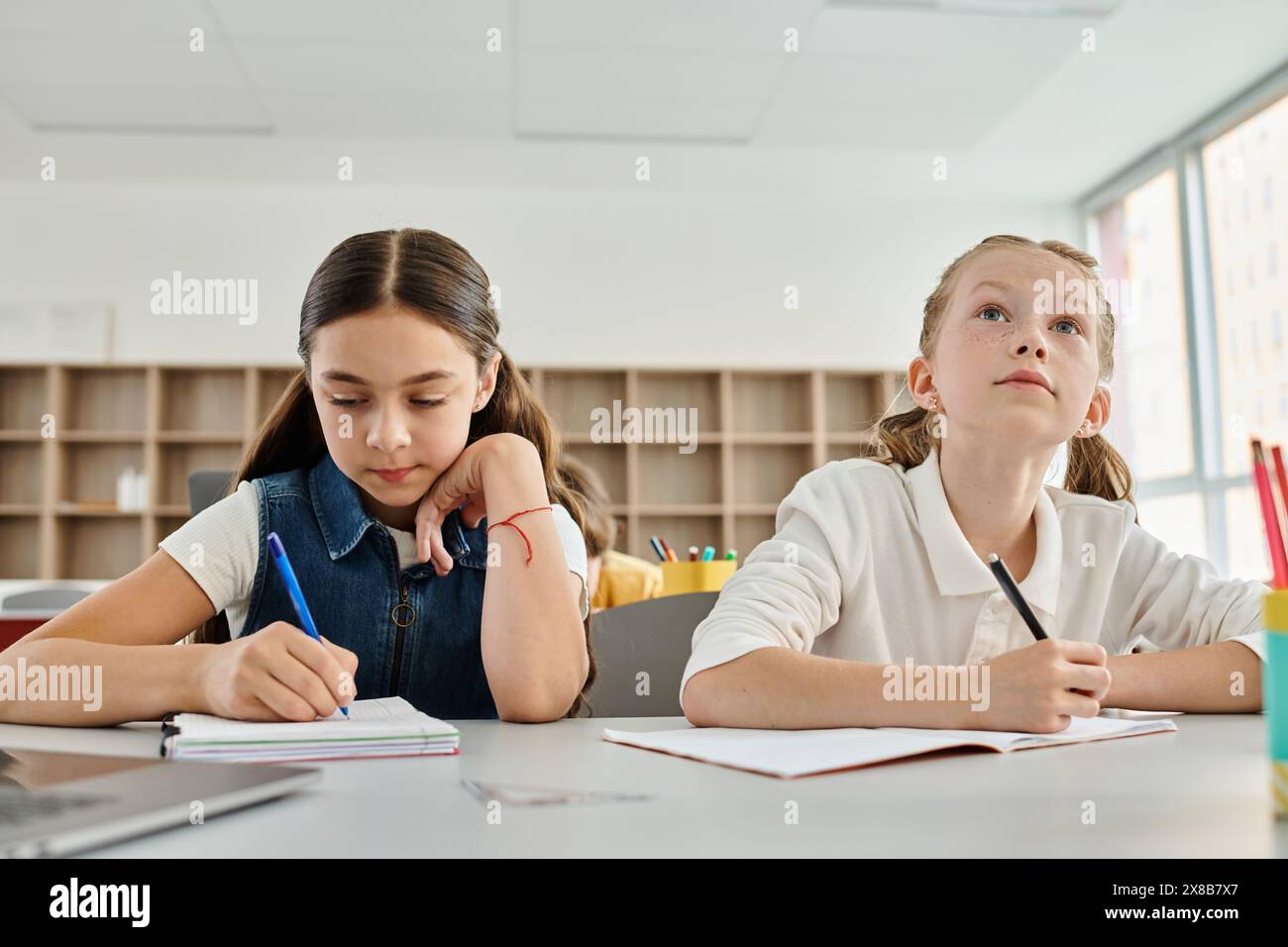 Two young girls actively participating in a classroom Stock Photo - Alamy