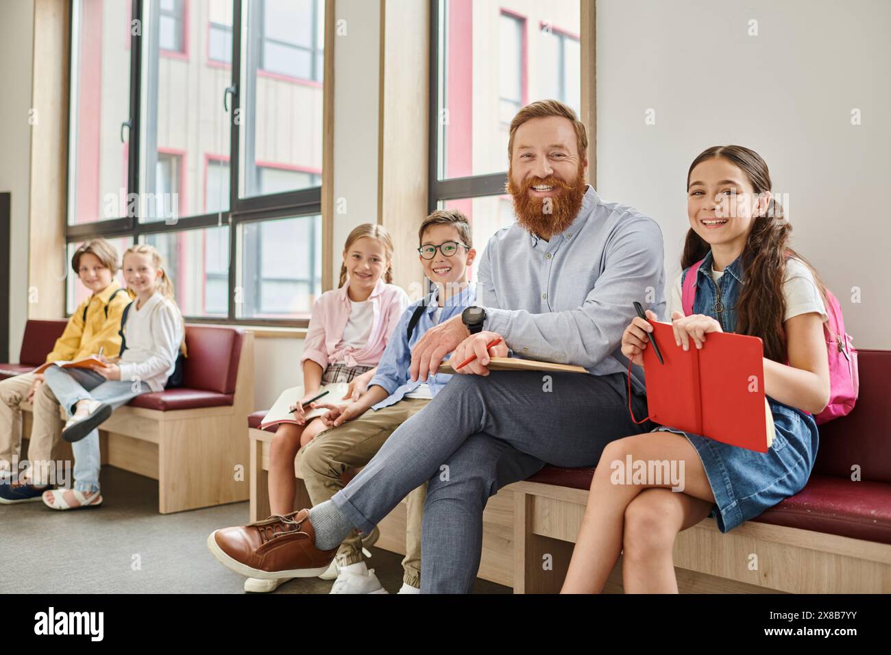 A group of people, including children and adults, sit patiently in a colorful waiting room Stock ...