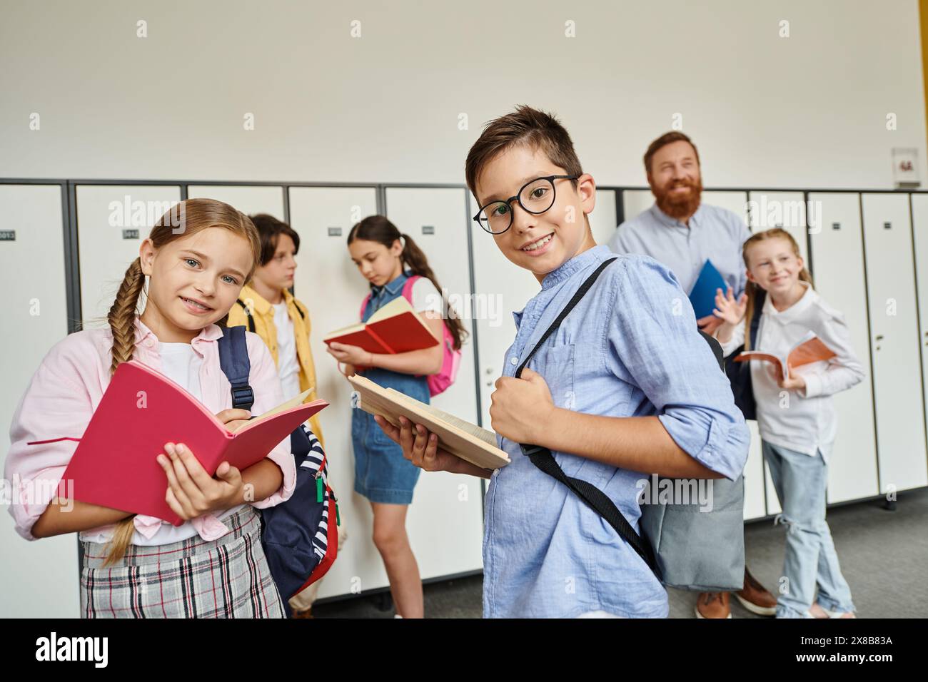 A diverse group of children, guided by their male teacher, stand ...