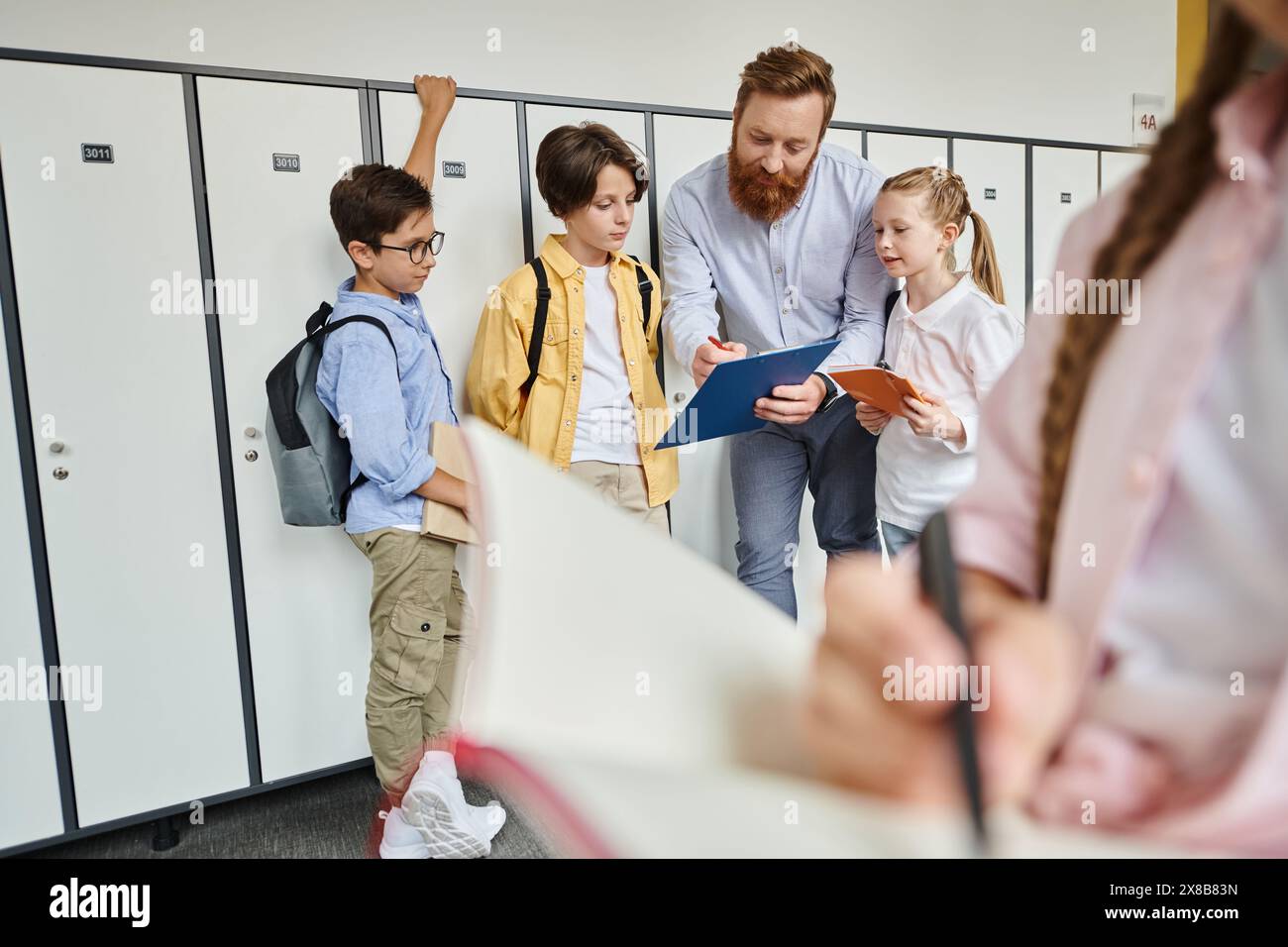 A man teacher is instructing a group of kids standing near lockers in a ...
