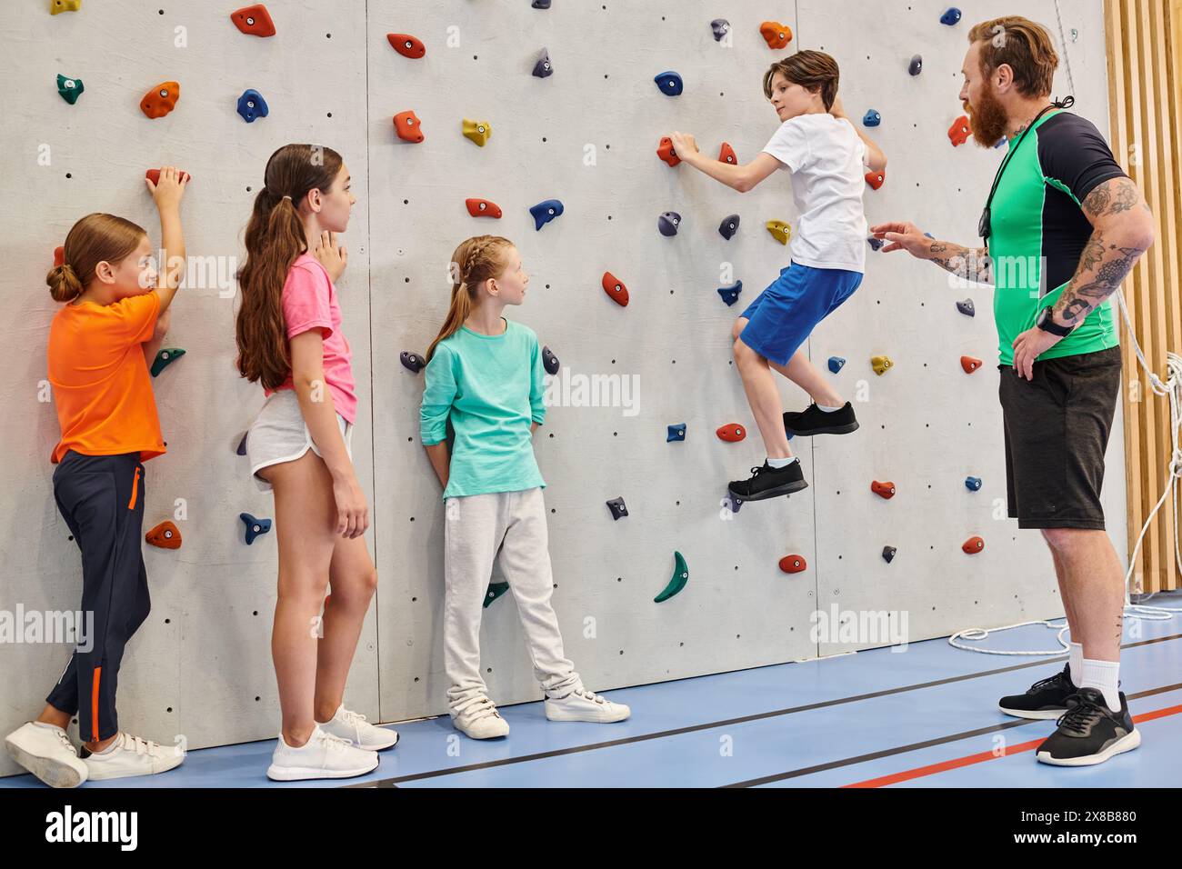 A diverse group of kids are energetically climbing and exploring a wall ...