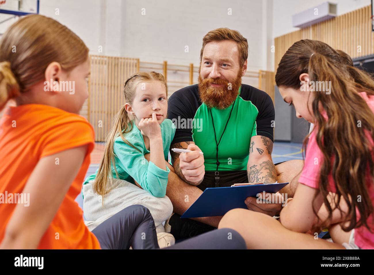 A bearded man sits on the basketball court surrounded by a diverse ...