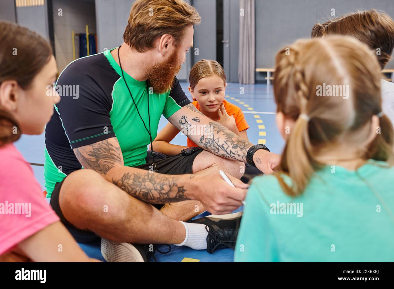 A man sitting on the floor surrounded by a group of diverse children ...