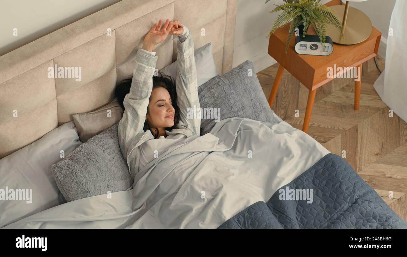 Happy woman stretching lying bed lazy comfortable girl female home hotel rest enjoyment smile ...