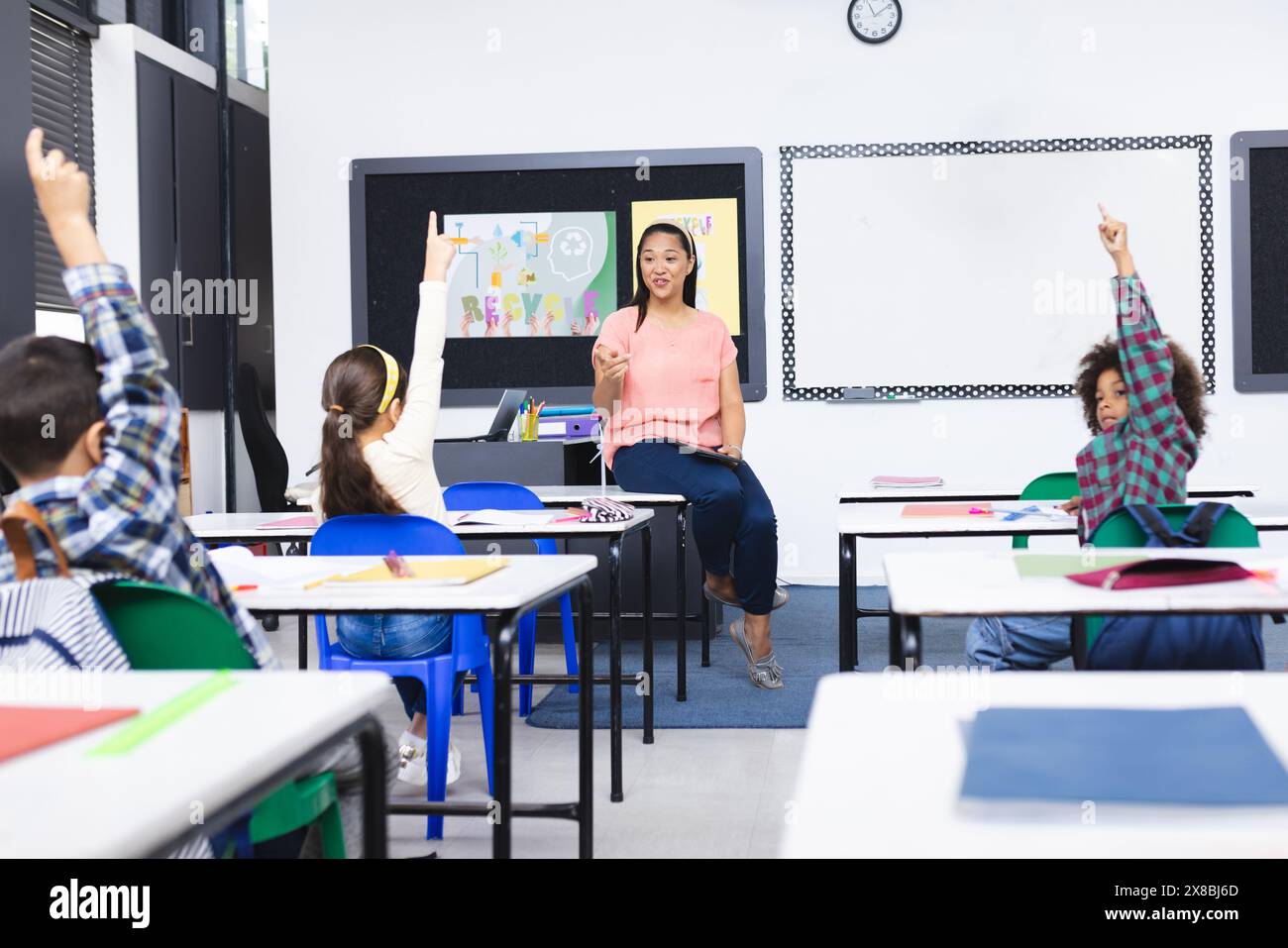 In school, young biracial female teacher explaining in classroom ...
