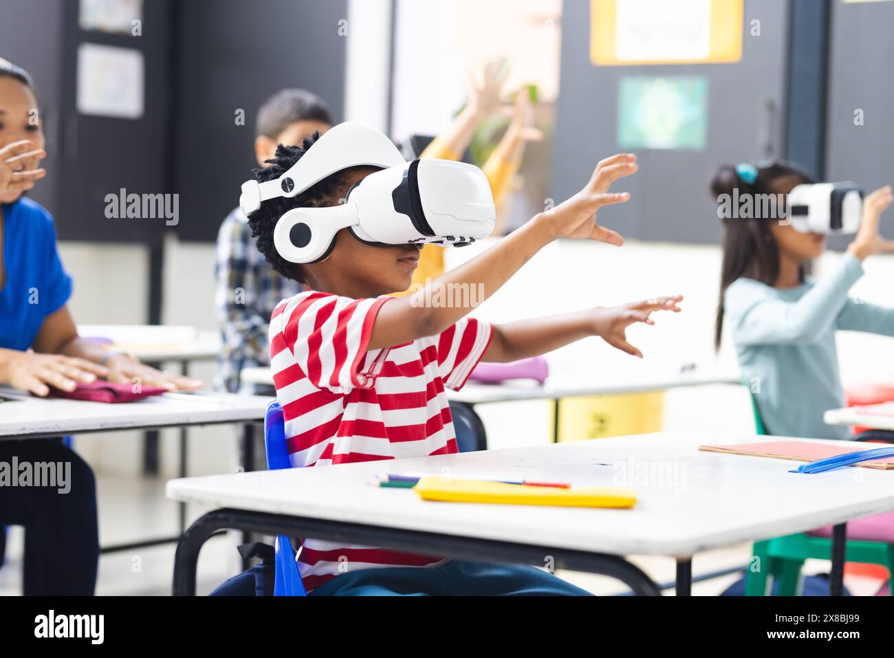 In school, diverse students wearing virtual reality headsets are ...