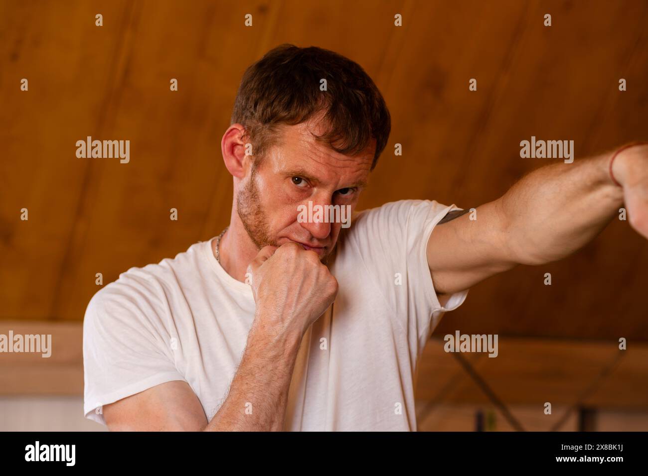 A man is standing in a boxing stance, with a serious expression. He ...