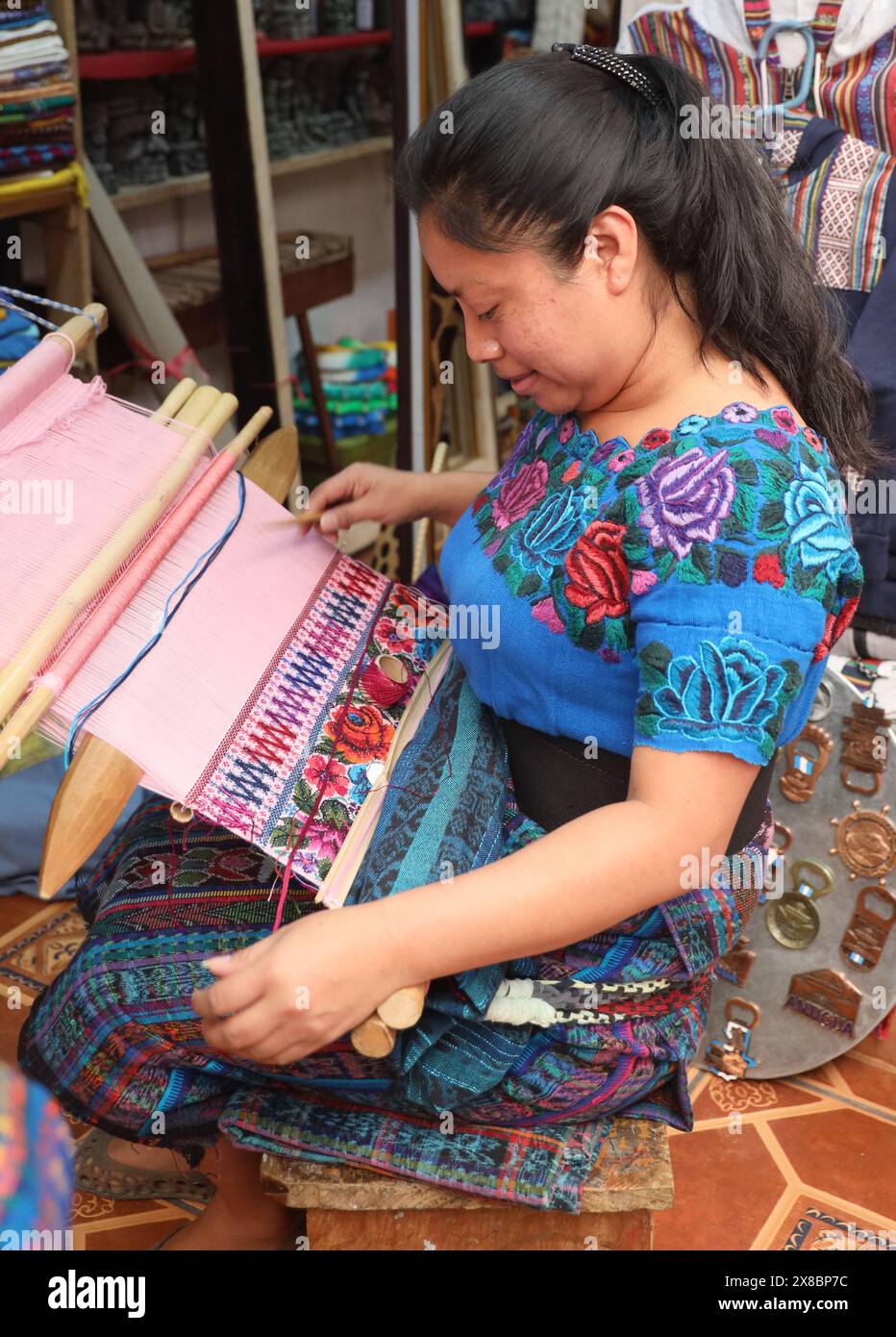 Indigenous Mayan woman using a back strap loom to weave fabric ...
