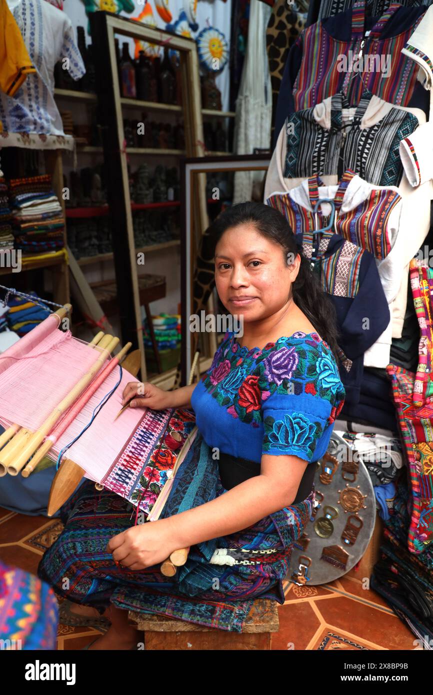 Indigenous Mayan woman using a back strap loom to weave fabric ...