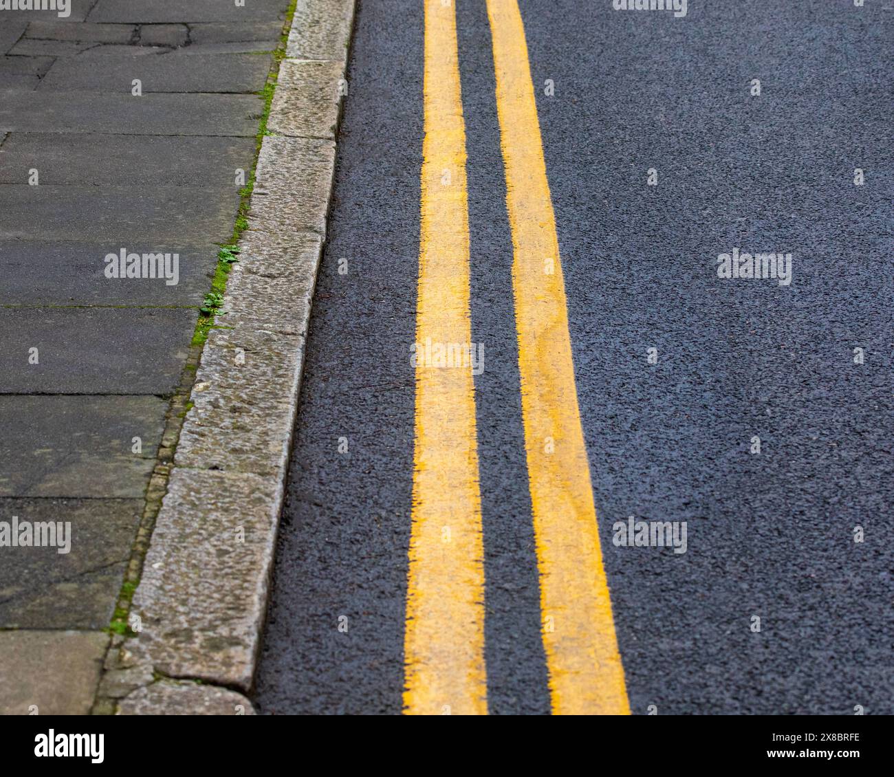 Close-up of double yellow lines on a road Stock Photo - Alamy