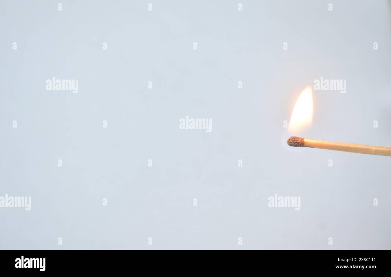 red head matchstick lighting on in white background Stock Photo - Alamy
