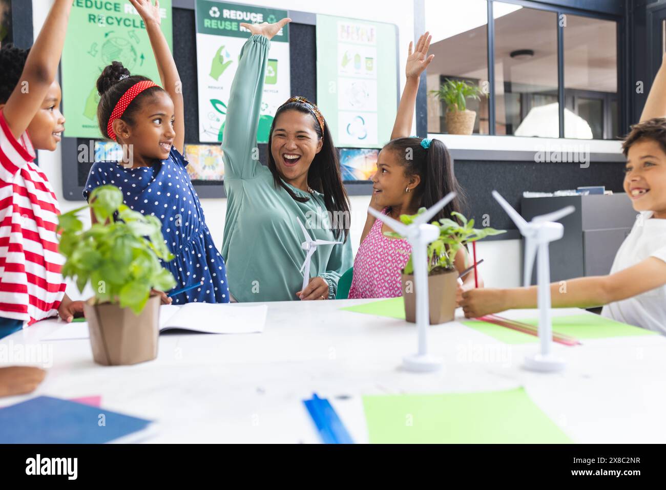 In school, middle-aged Asian teacher and diverse children are ...