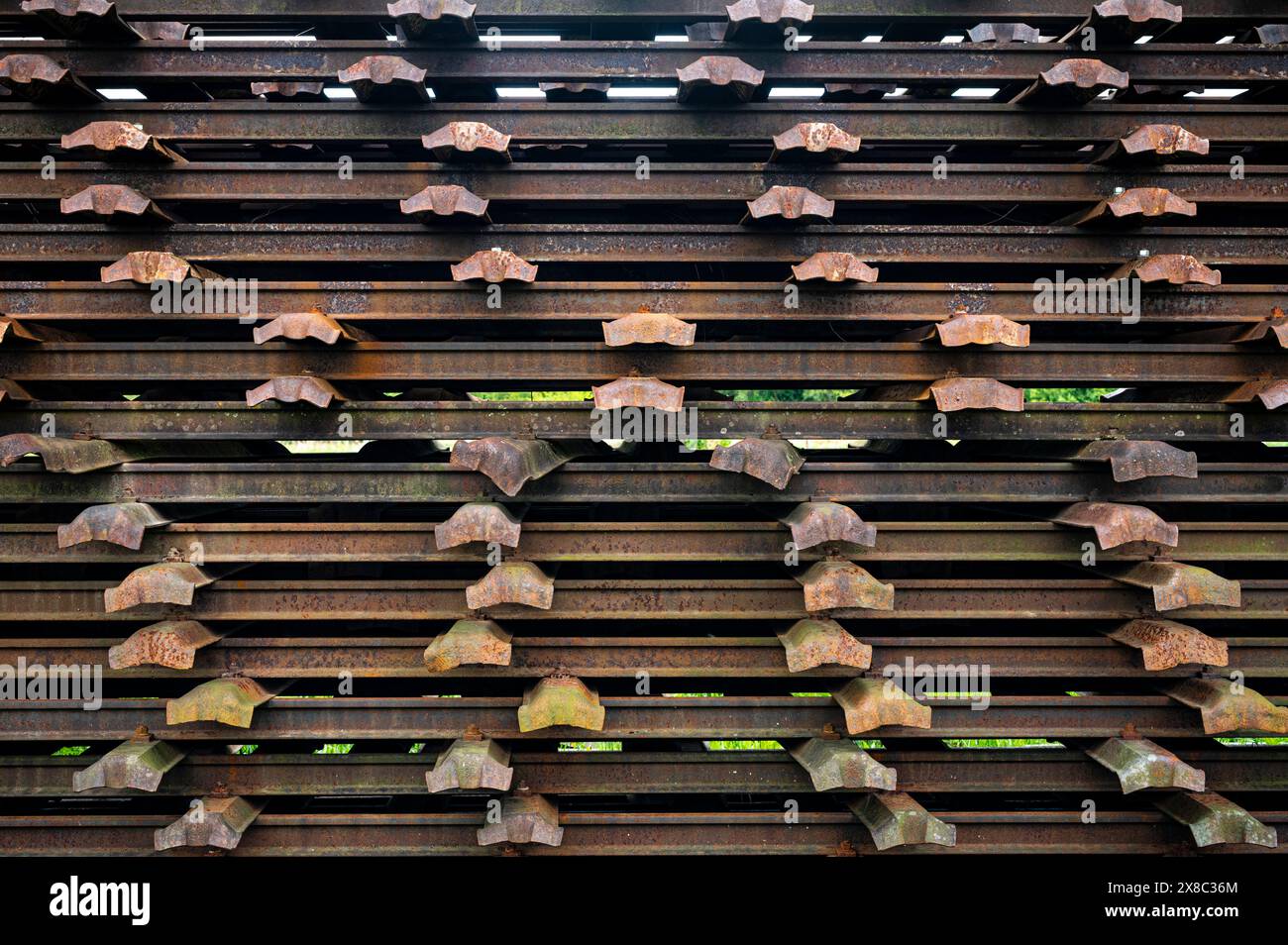 rusted pieces of railway and metal sleepers stacked together outside ...