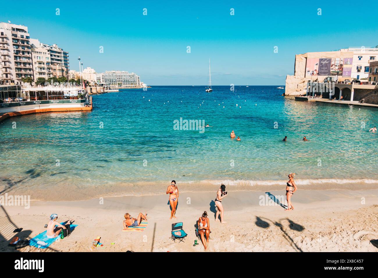 swimmers and sunbathers relax in the shallow turquoise waters at the ...