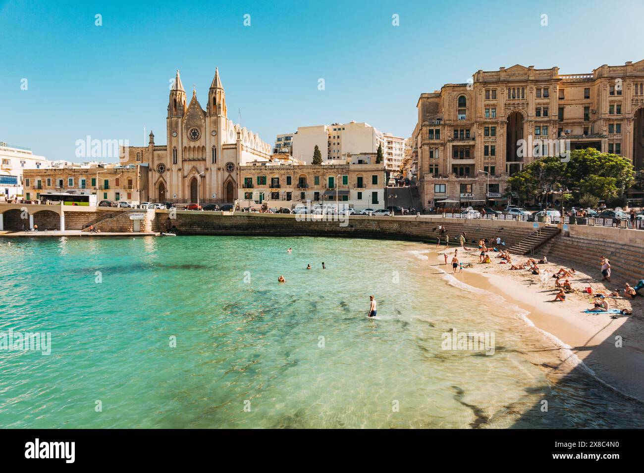 People bathe in the shallow turquoise waters at Balluta Bay Beach in St ...