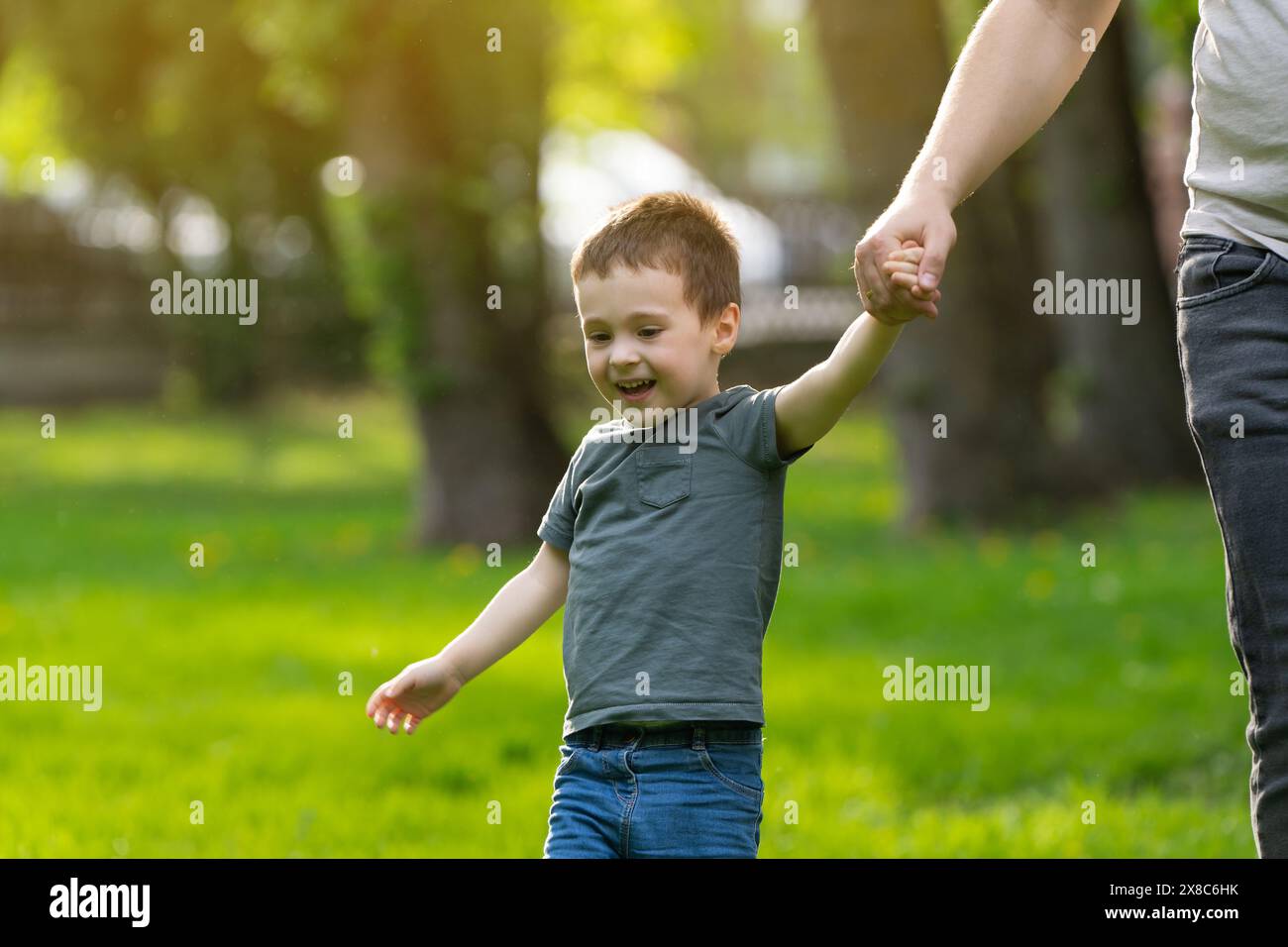 Happy three year old toddler boy walks hand in hand with dad in the ...